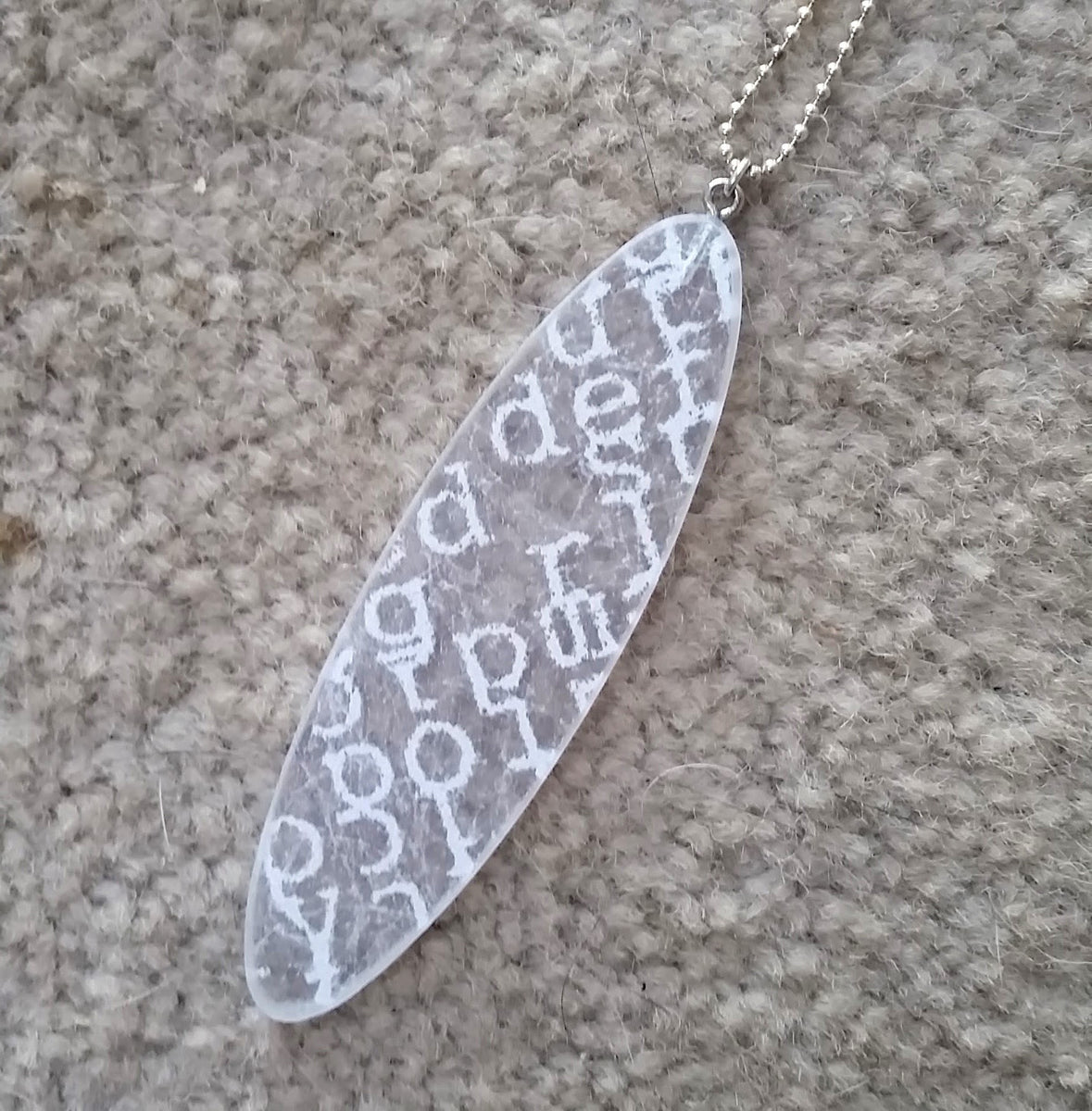 Large recycled plastic pendant with white type – Amy Pfaffman